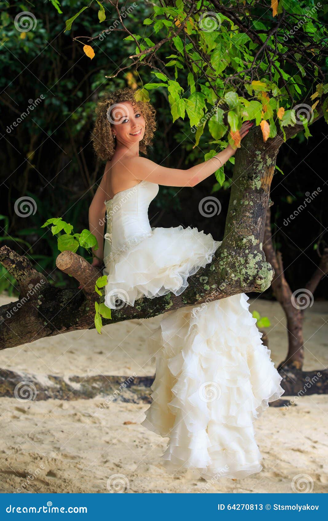 Blonde Bride In Fluffy Dress Sits On Tree Trunk Smiles Stock Image