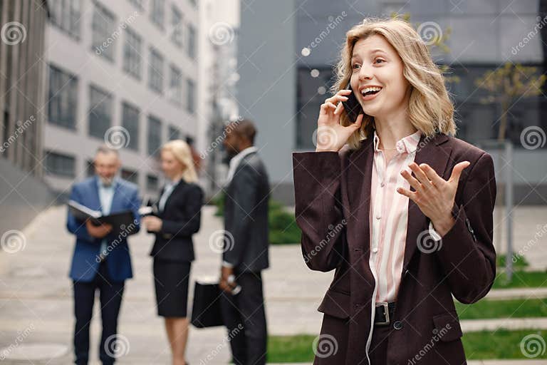 Blonde Businesswoman Standing And Talking On The Phone In Front Of