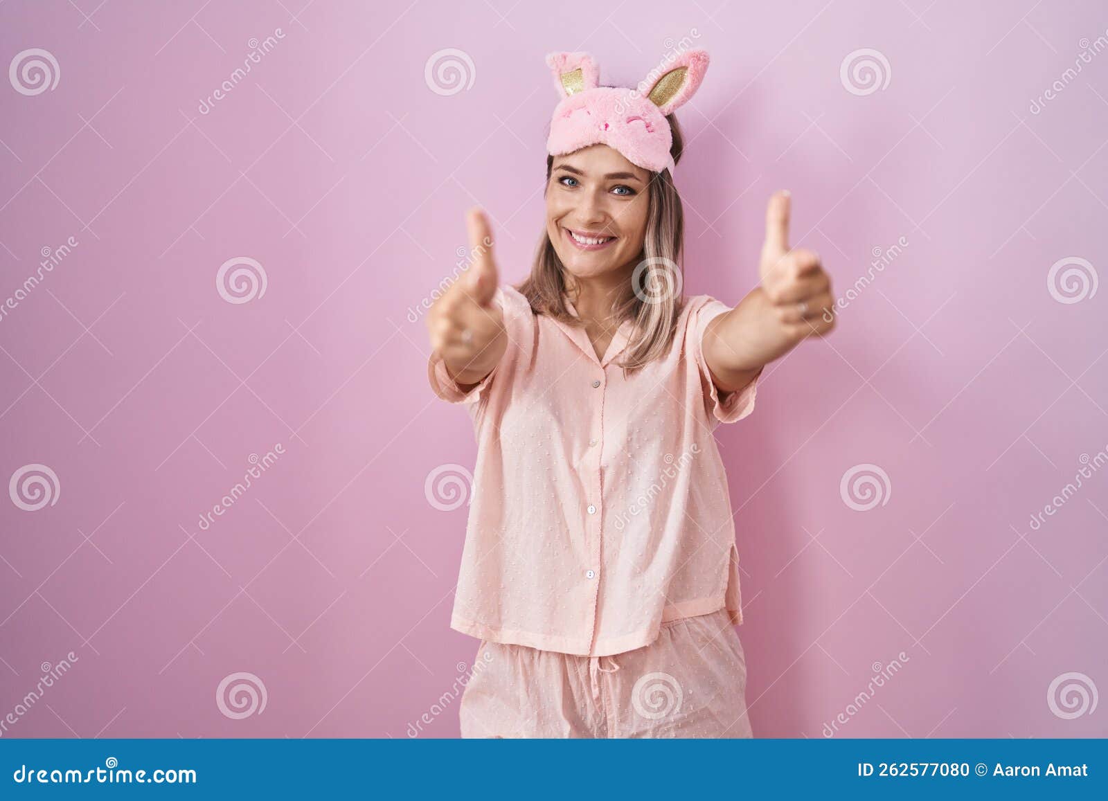Blonde Caucasian Woman Wearing Sleep Mask And Pajama Pointing Fingers