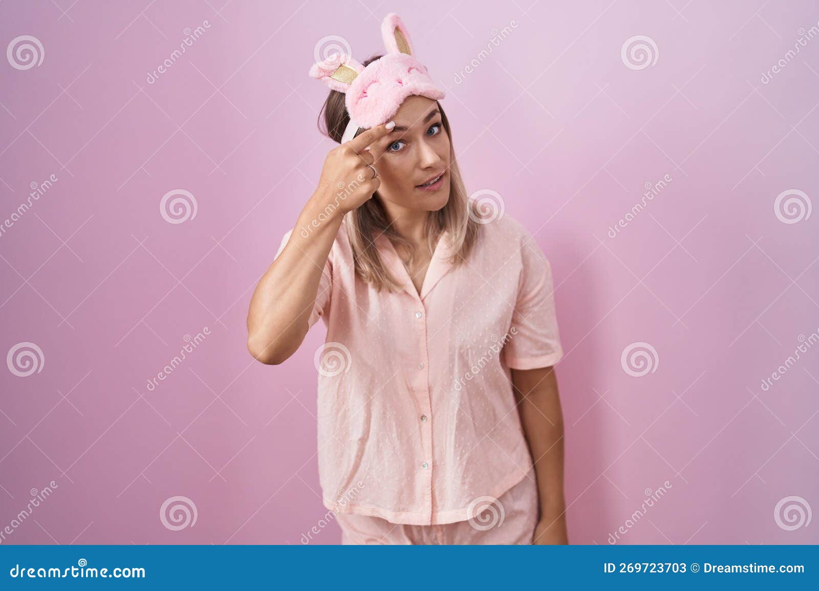 Blonde Caucasian Woman Wearing Sleep Mask And Pajama Pointing Unhappy