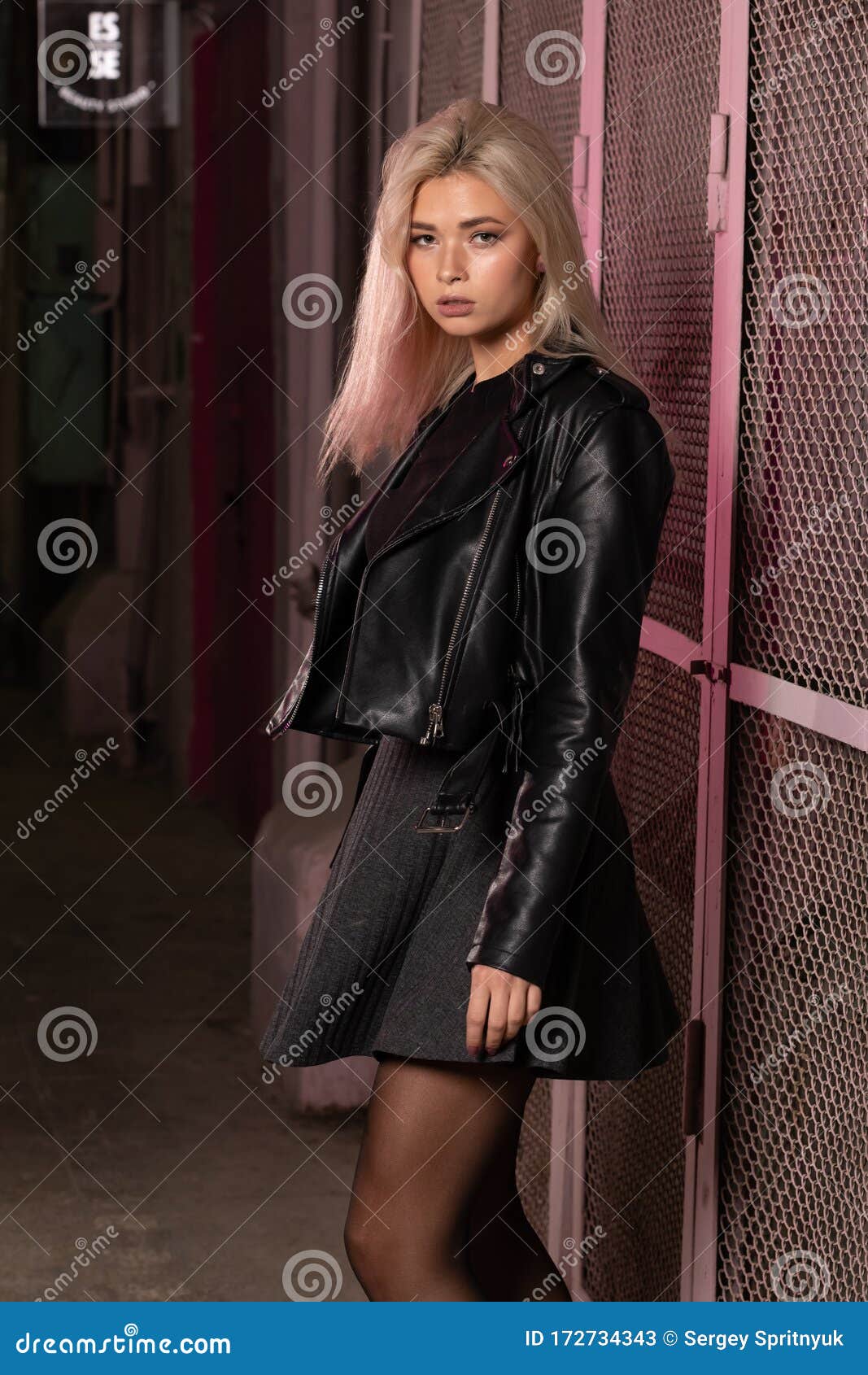 Blonde Girl In A Black Leather Jacket Posing On A Dark Background And