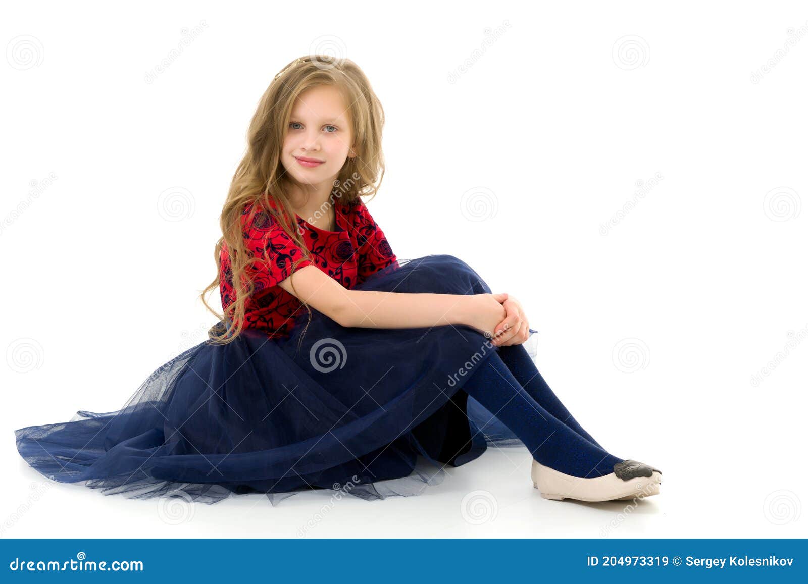 Blonde Girl In Stylish Tulle Dress Sitting On Floor Hugging Her Knees