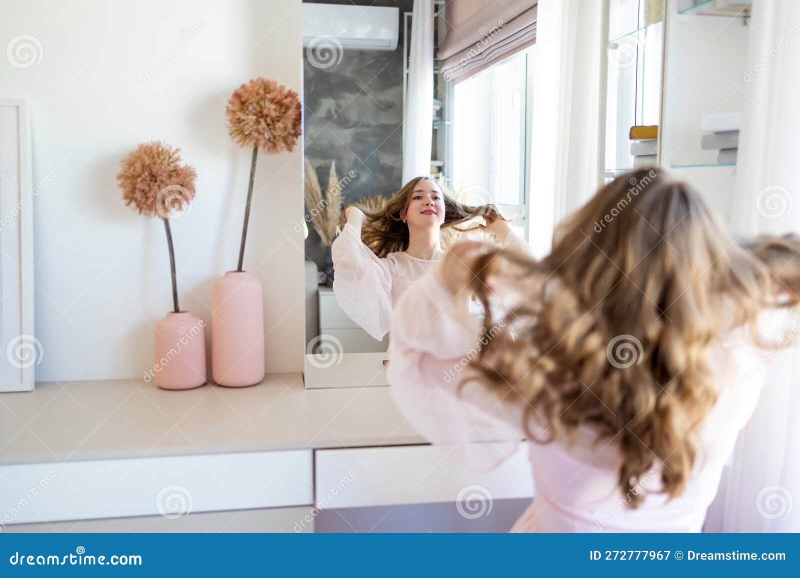 Girl Touching Her Hair And Smiling While Looking In The Mirror Stock