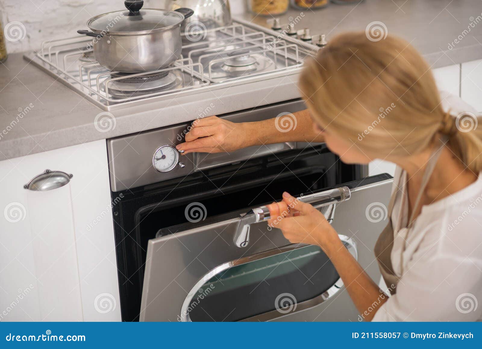 Blonde Woman Opening the Oven in the Kitchen while Cooking Dinner Stock ...