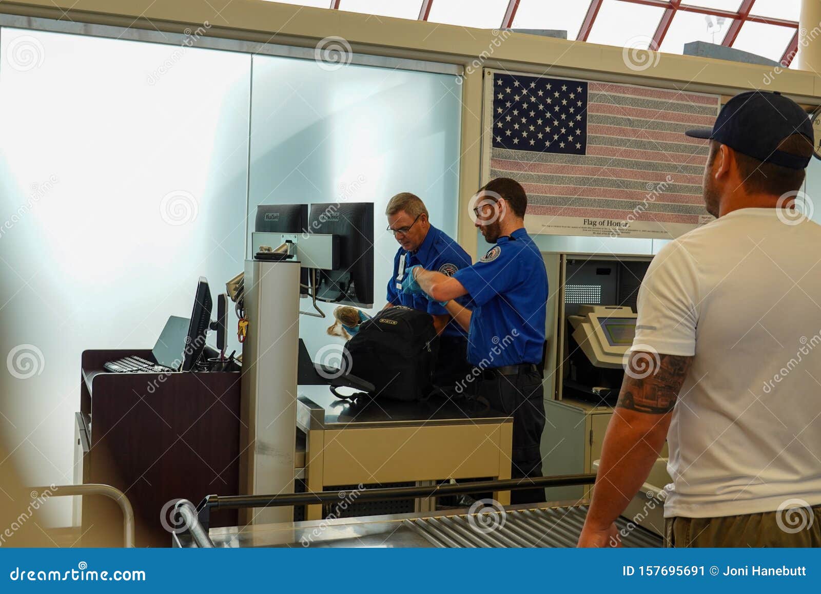 Two TSA Security Employees Checking a Backpack for Potentially ...