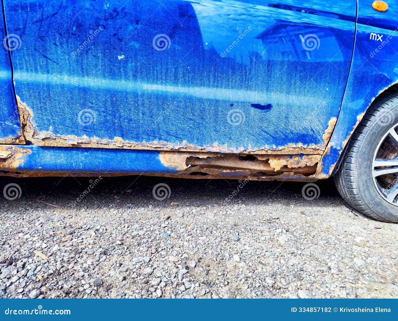 A Blue Car Shows Significant Rust Damage Along the Lower Side Panel ...