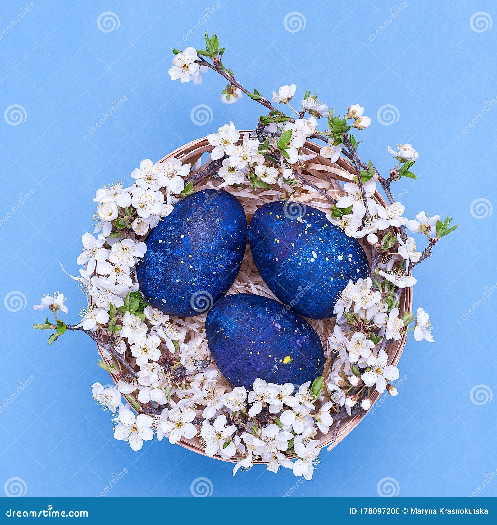Blue Easter Eggs in a Basket with Flowers on a Blue Background. Square ...