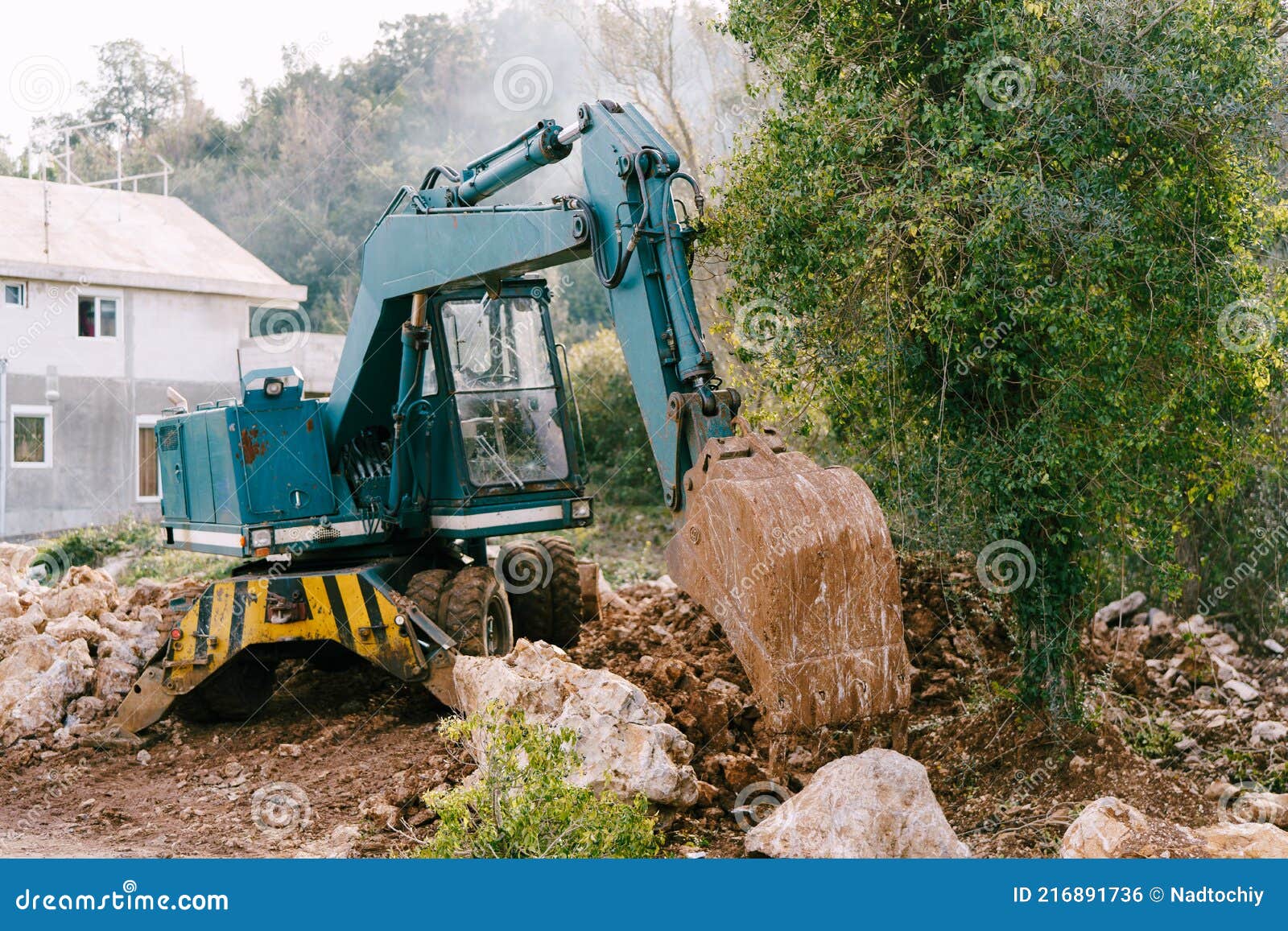 Blue Excavator Works at a Construction Site Against the Backdrop of a ...