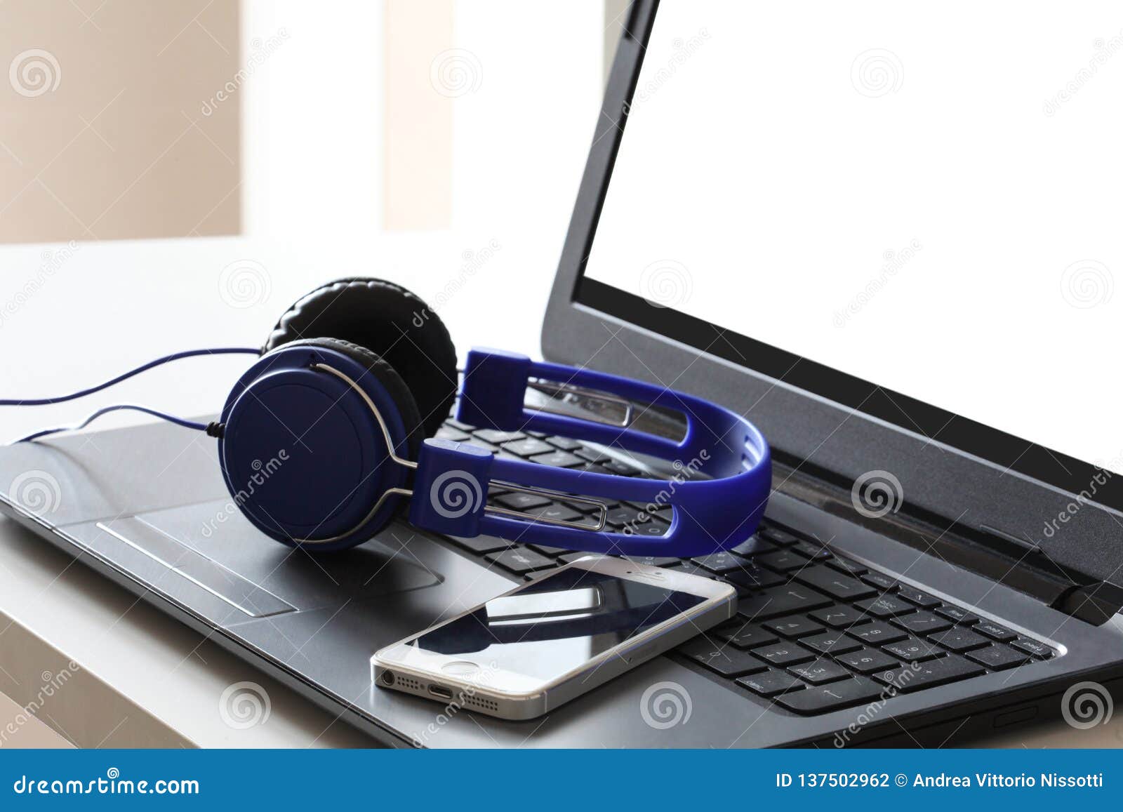 Blue Headphones and a Smart Phone Rest on a Laptop Computer with ...