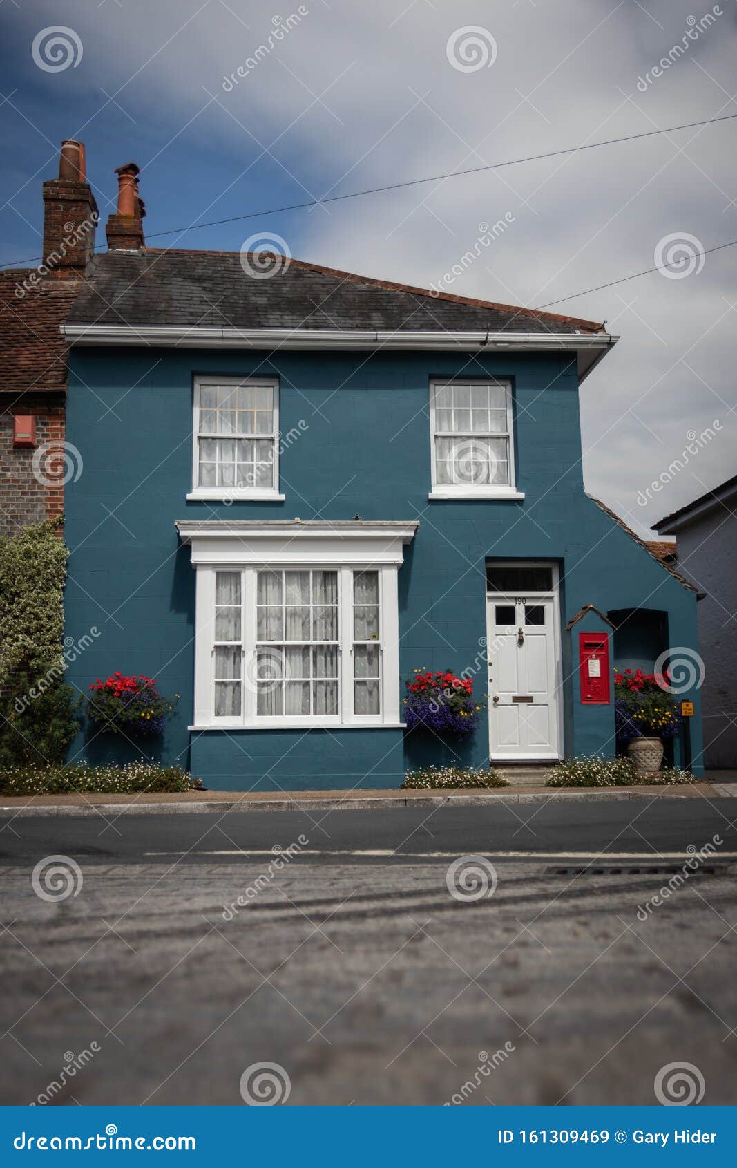 A Blue Old English Cottage with a Red Post Box in the Wall Editorial ...