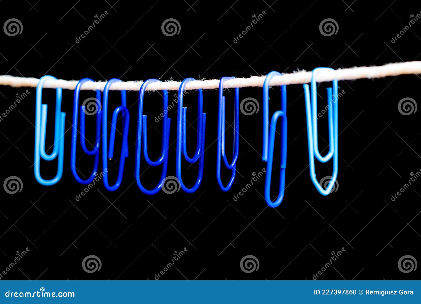 Blue Paper Clips Suspended on a String on a Black Background Stock ...