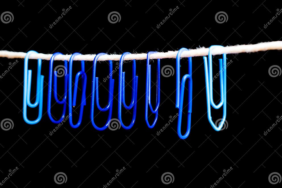 Blue Paper Clips Suspended on a String on a Black Background Stock ...