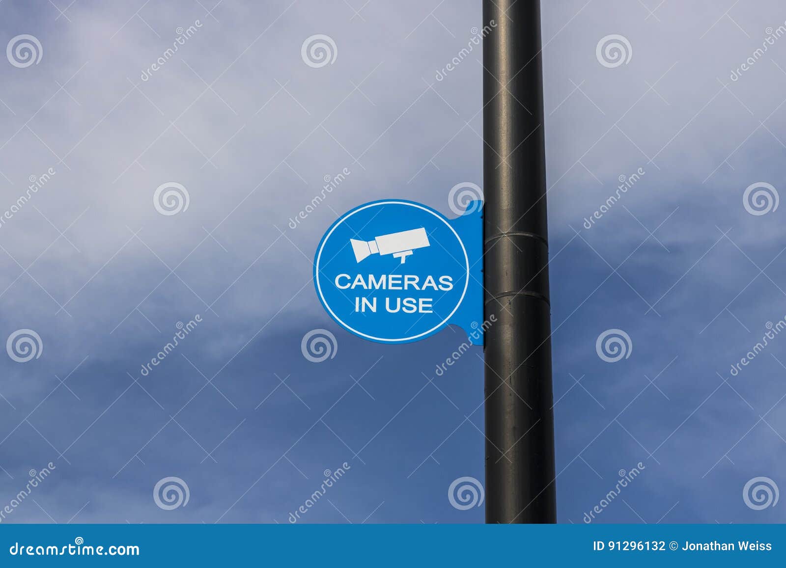 Blue Security Camera in Use Sign on Black Post and Partly Sunny ...