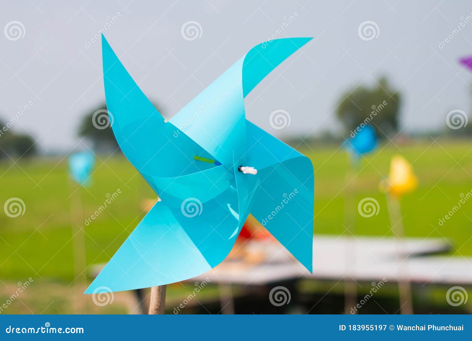 Blue Toy Windmill with Four Points with a Background Image of Lush ...