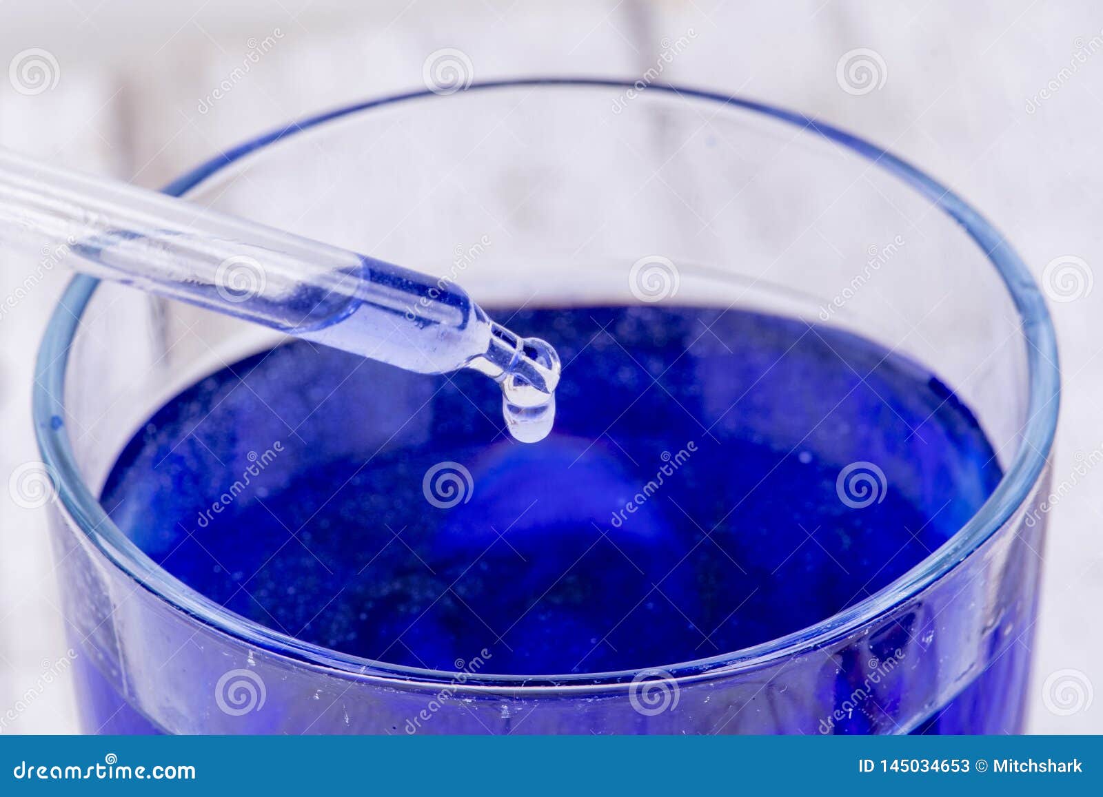 Pipette Drops a Drop of Liquid into a Blue Liquid Container Stock Image ...