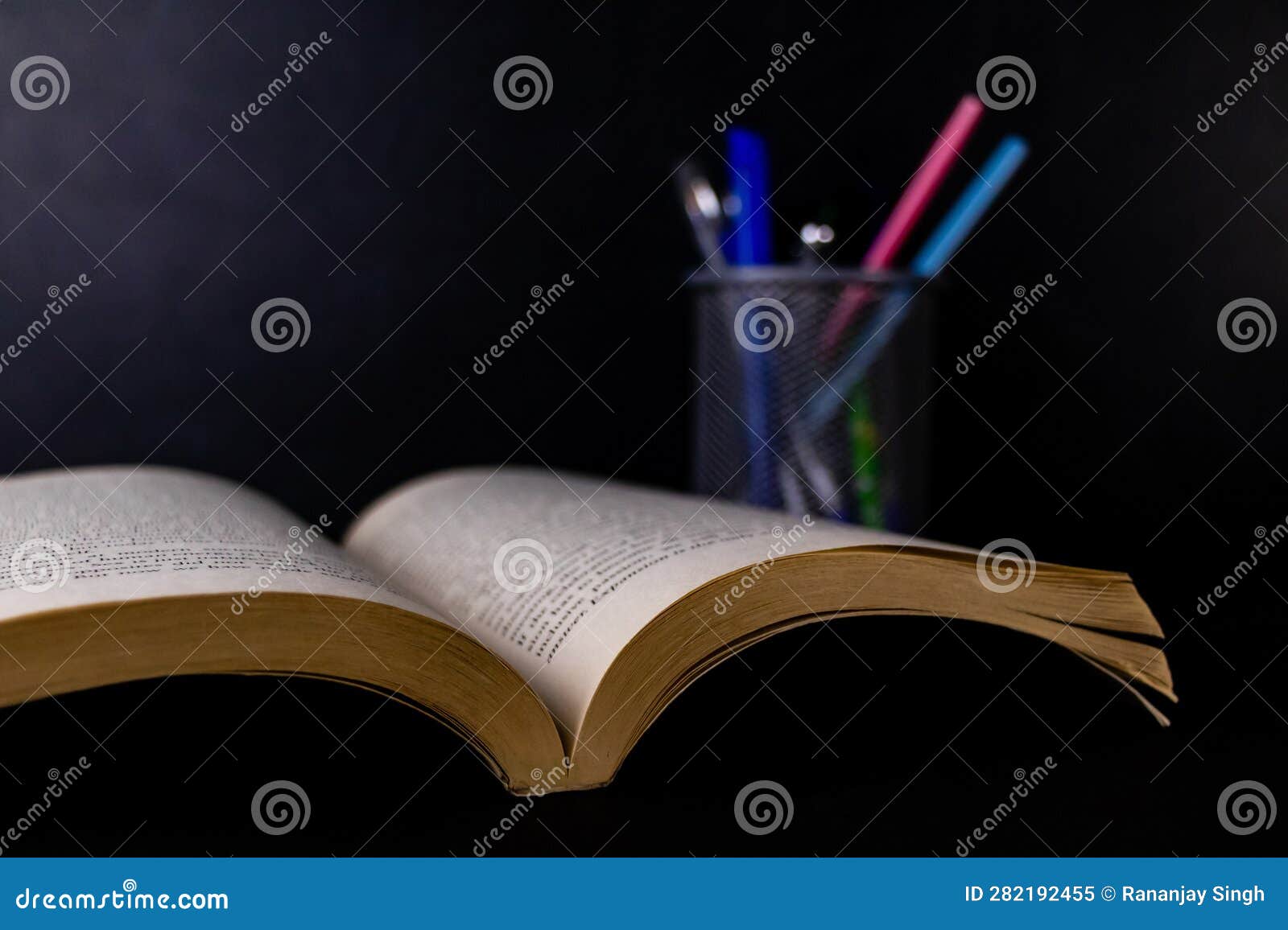 A Blurred Pen Stand with Opened Book in the Foreground -Teaching ...