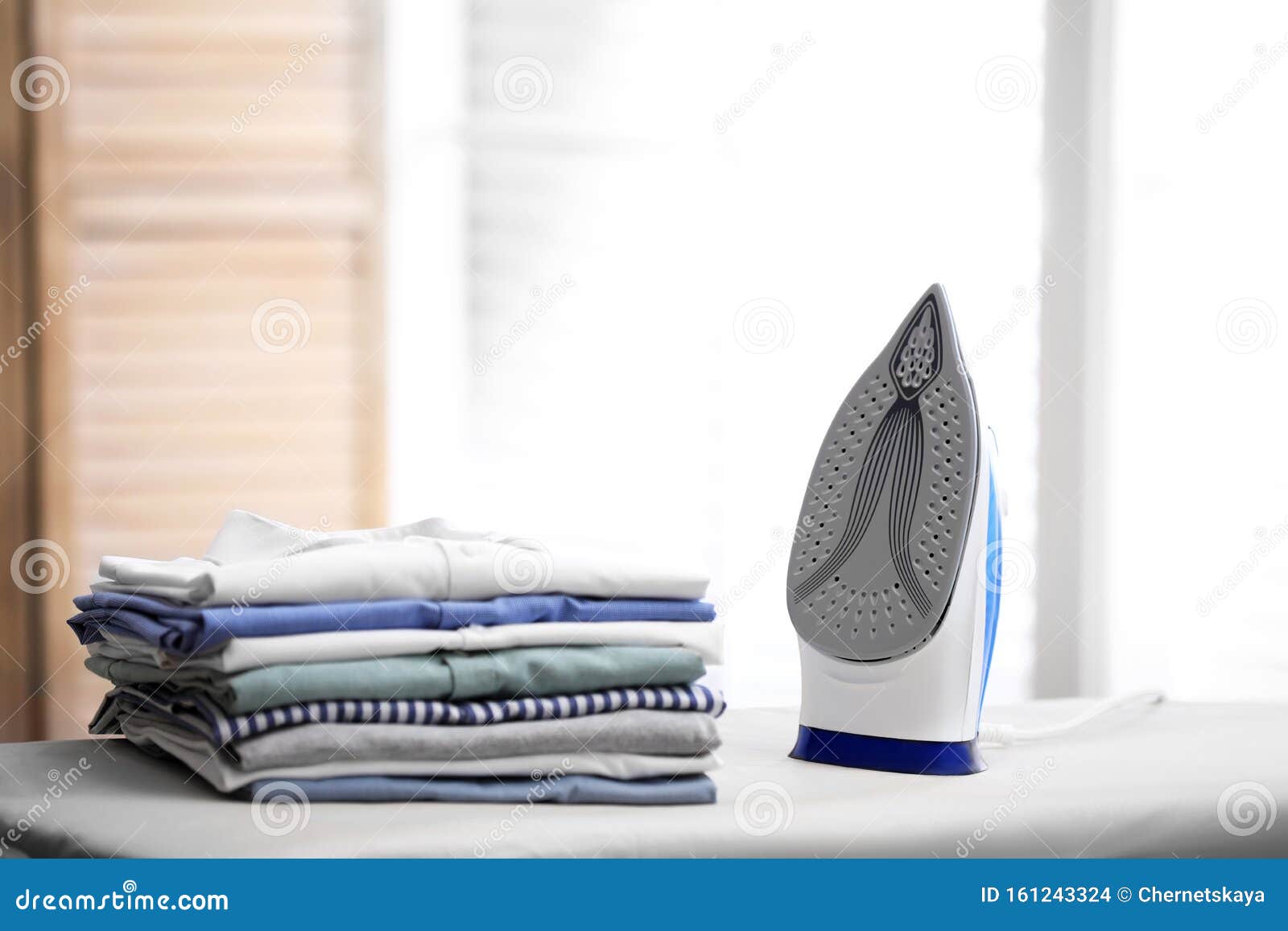 Board with Modern Iron and Stack of Clothes. Laundry Day Stock Photo ...