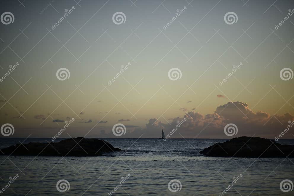 Boat on the Horizon at Sunset with Two Parallel Rocks in the Foreground ...