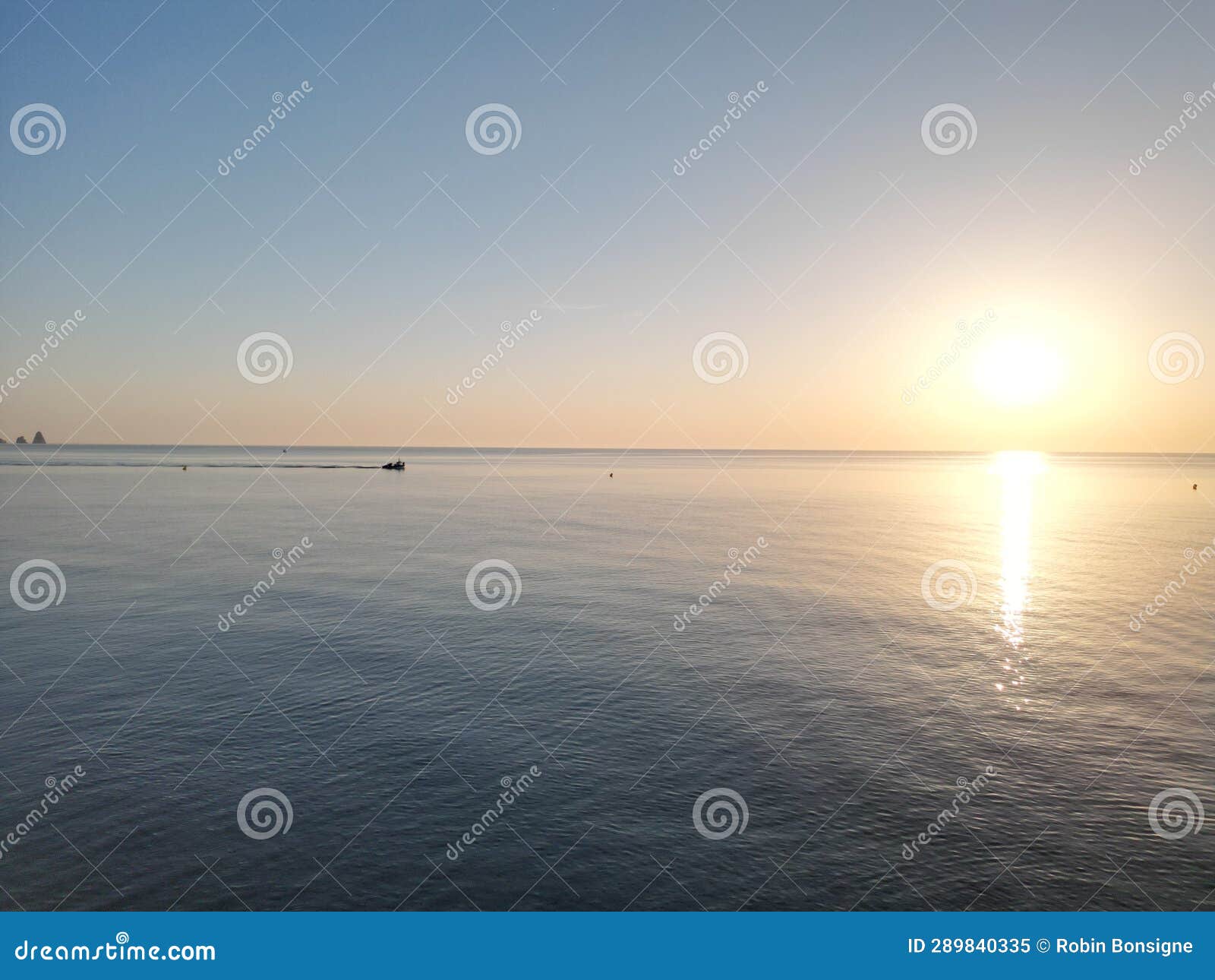 A Boat Sailing on the Water and Heading Towards the Rising Sun Stock ...