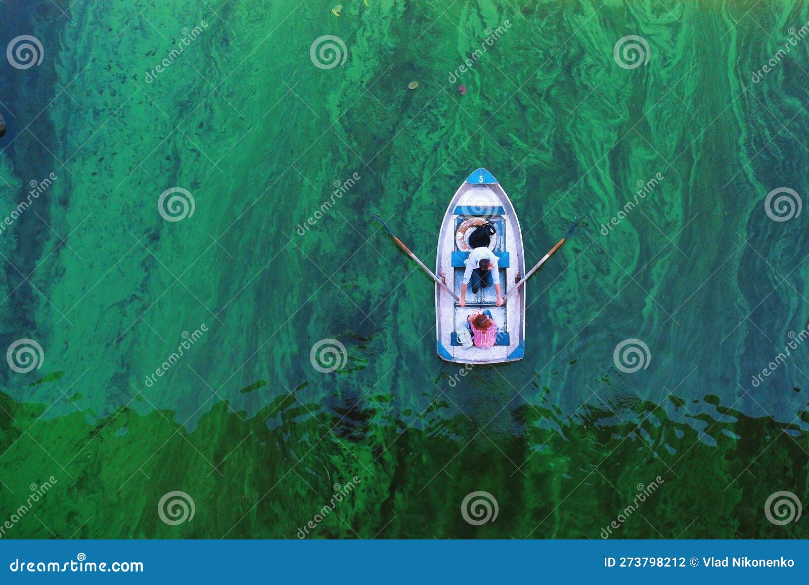 A Boat with Two Sailors Floats on Green Water Stock Photo - Image of ...