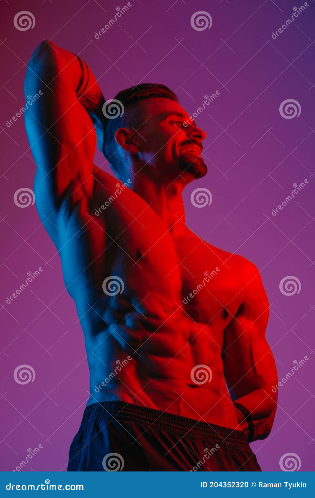 A Bodybuilder is Posing with Arms Behind His Back Under the Blue and ...