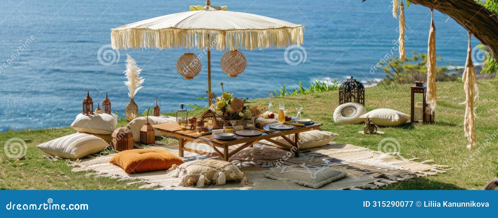 A Boho Picnic Setup on Lush Grass Near the Ocean, Featuring a Cozy ...
