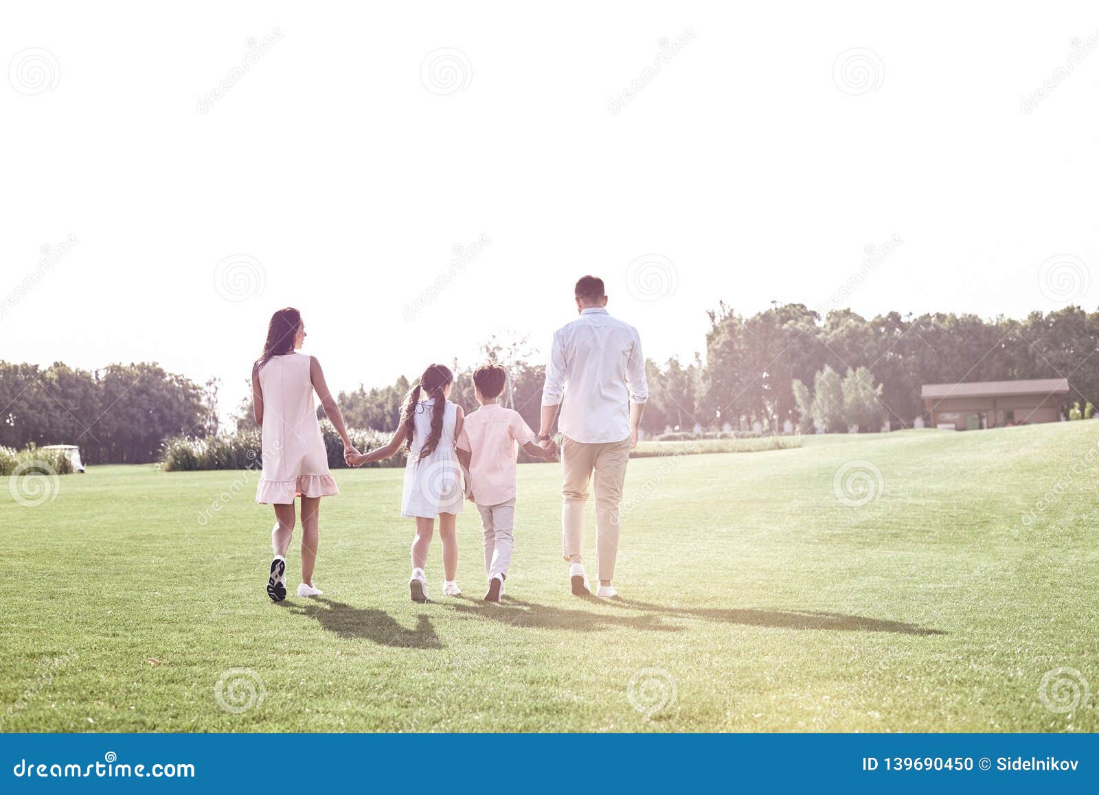 Bonding. Family of Four Walking on Grassy Field Back View Stock Photo ...