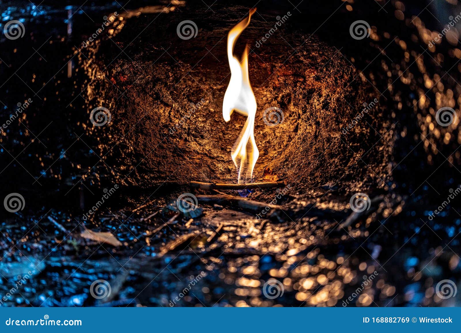 Bonfire in a Cave Surrounded by Rocks and Branches during the Rain ...