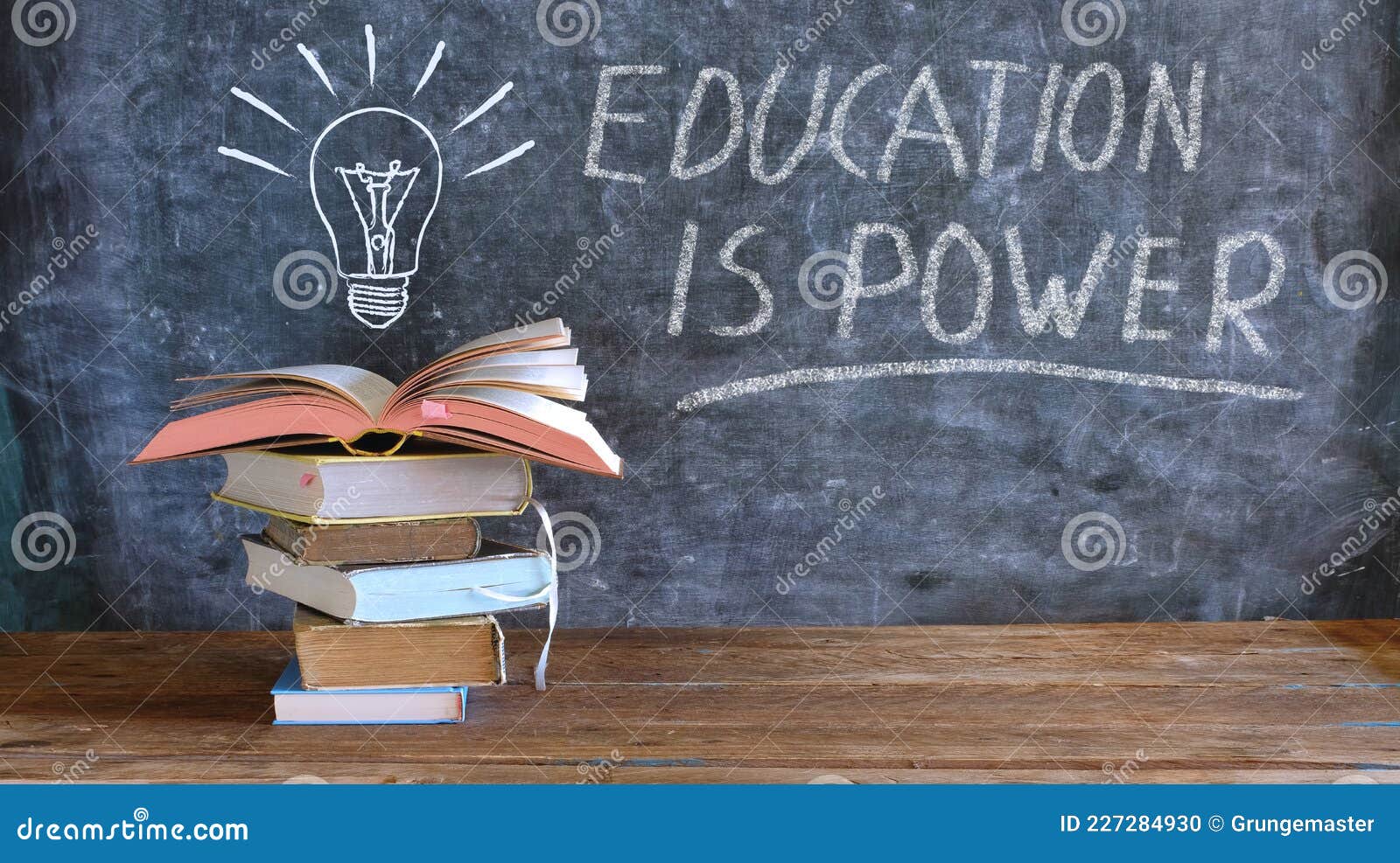 Books and Blackboard with Drawing of a Lightbulb and Slogan Education ...