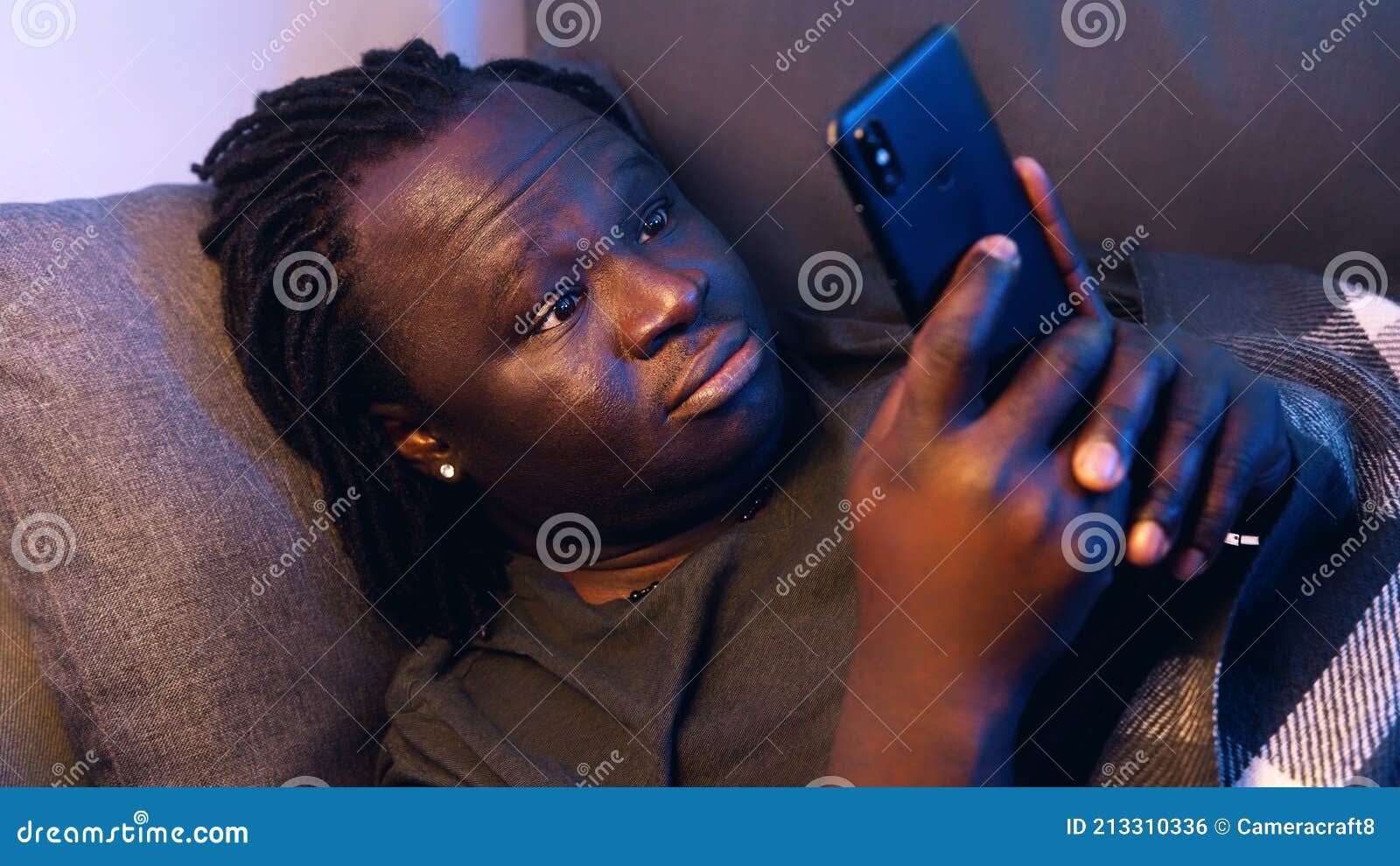 Bored Black Man Using Smartphone while Resting on the Couch Stock Photo ...