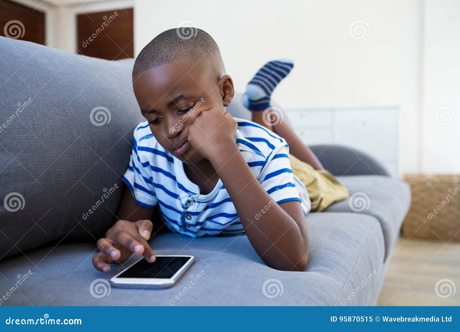 Bored Boy Lying on Sofa while Using Mobile Phone at Home Stock Image ...