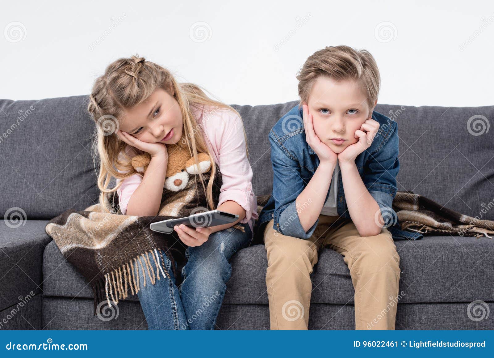 Bored Brother and Sister Sitting on Sofa and Holding Remote Control ...