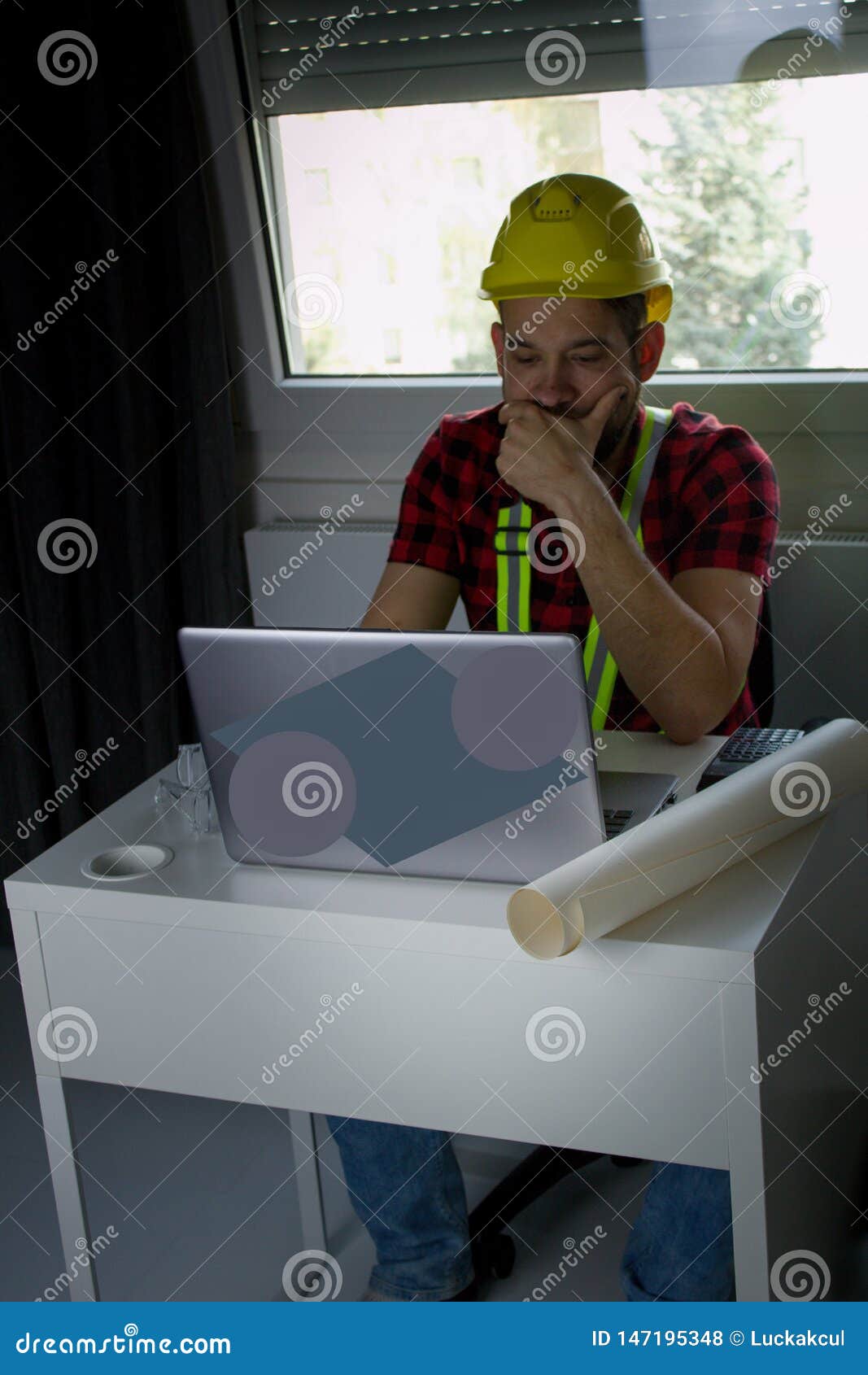 Bored Construction Worker is Sitting at His Desk at the Computer ...