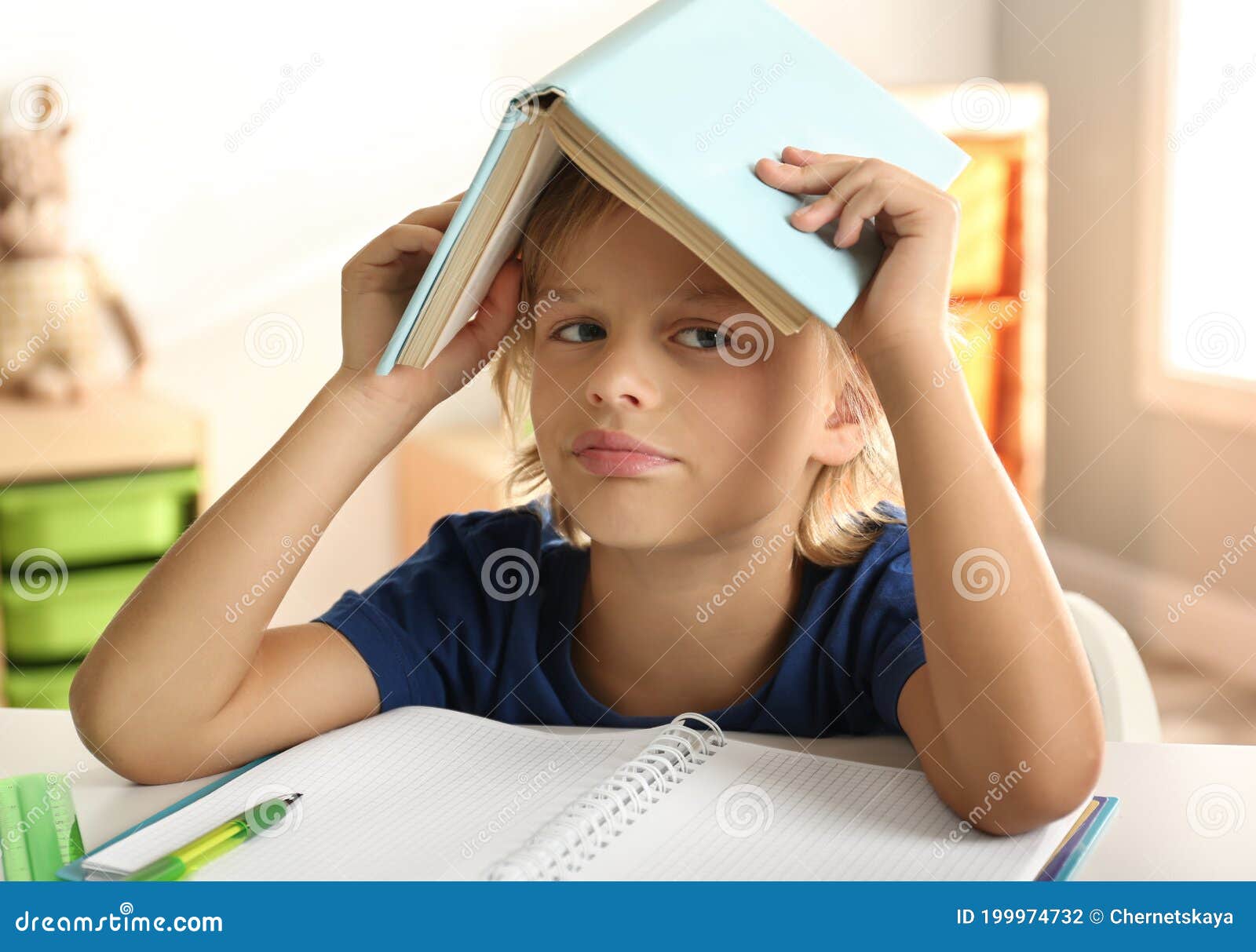 Bored Little Boy with Book on His Head Doing Homework at Table Indoors ...