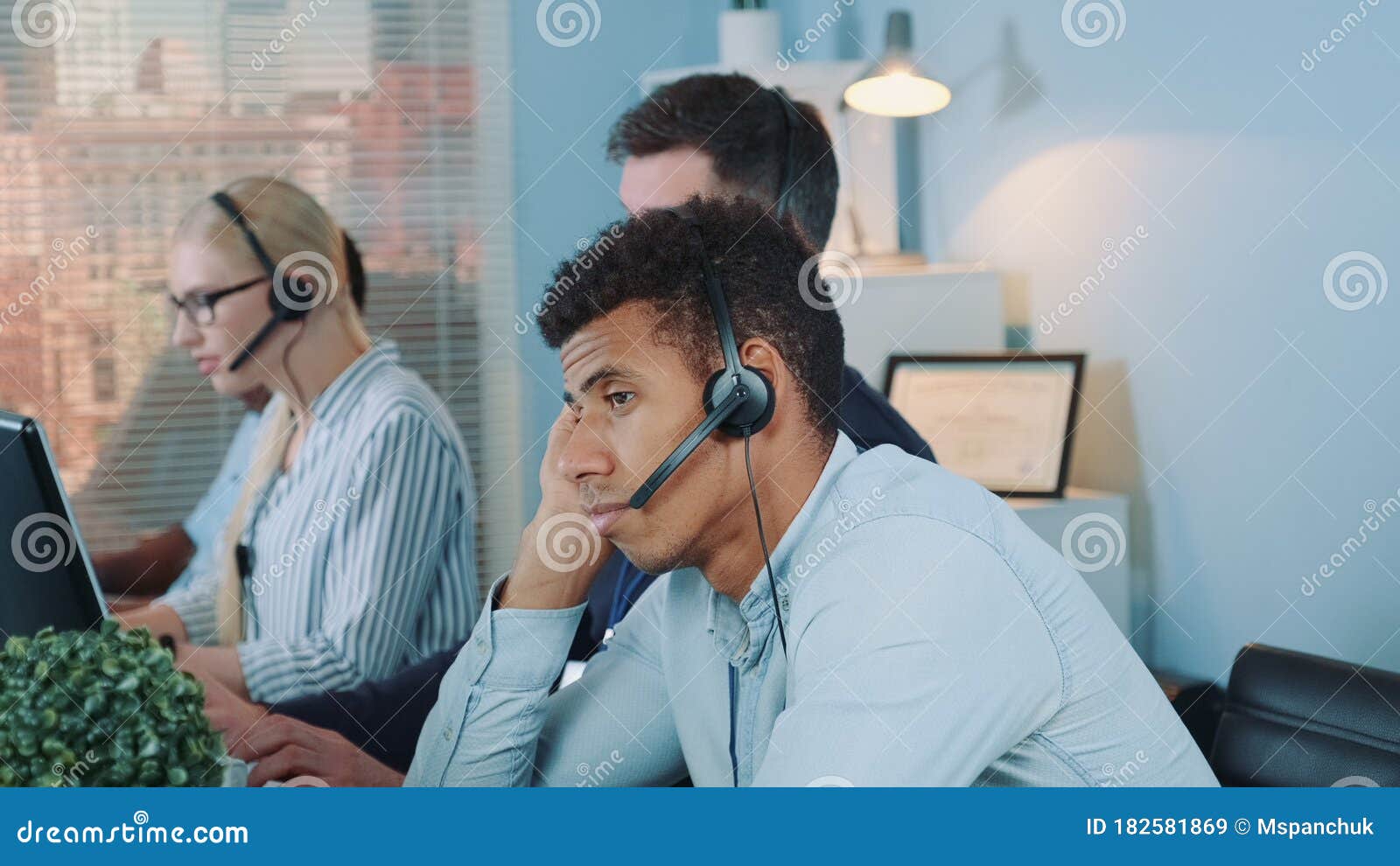 Bored Multiethnic Customer Support Operator Waiting for Telephone Call ...