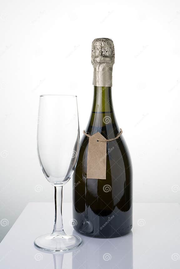 A Bottle of Alcohol with a Label on a String and a Glass on a Light ...