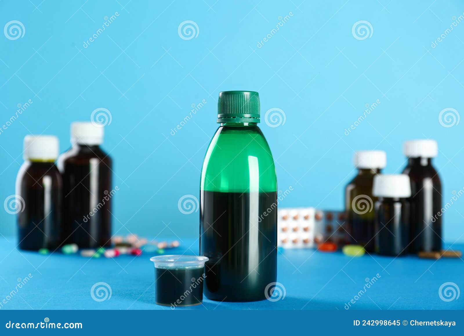 Bottle of Cough Syrup and Measuring Cup on Light Blue Background Stock ...
