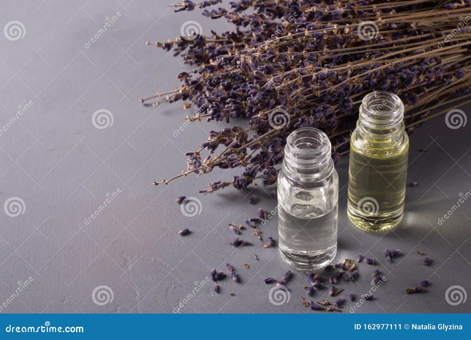 A Bottle of Lavender Essential Oil with Blue Flowers. Aromatherapy ...