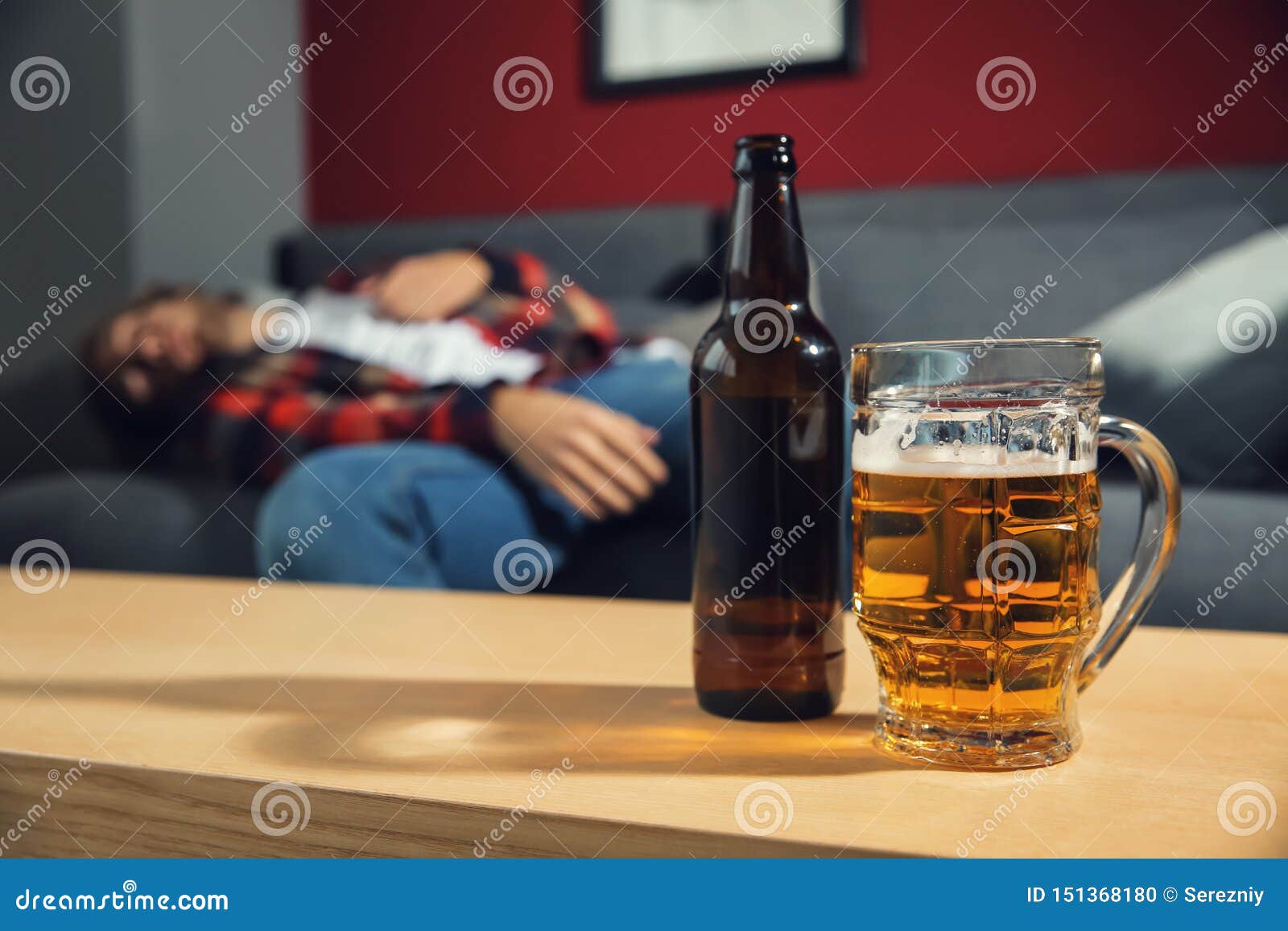 Bottle and Mug of Beer on Table and Blurred Drunk Man Sleeping on Sofa ...