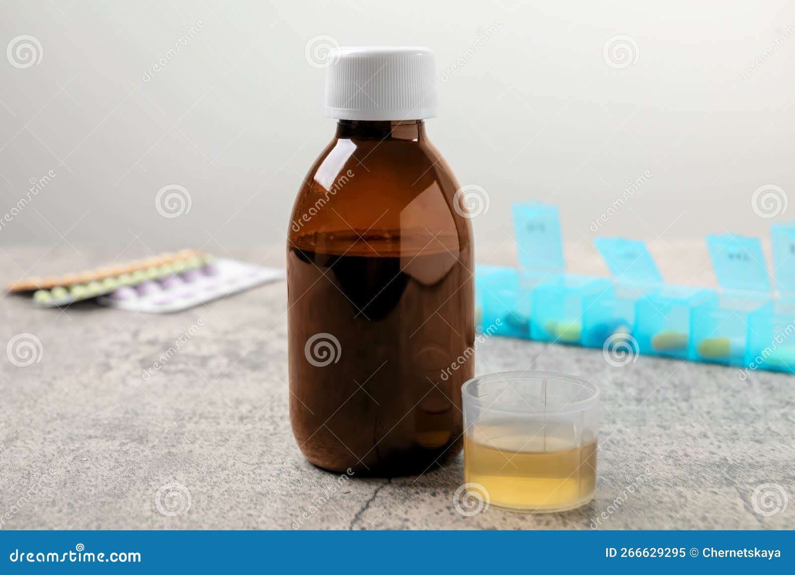 Bottle of Syrup and Measuring Cup on Light Grey Table. Cold Medicine ...