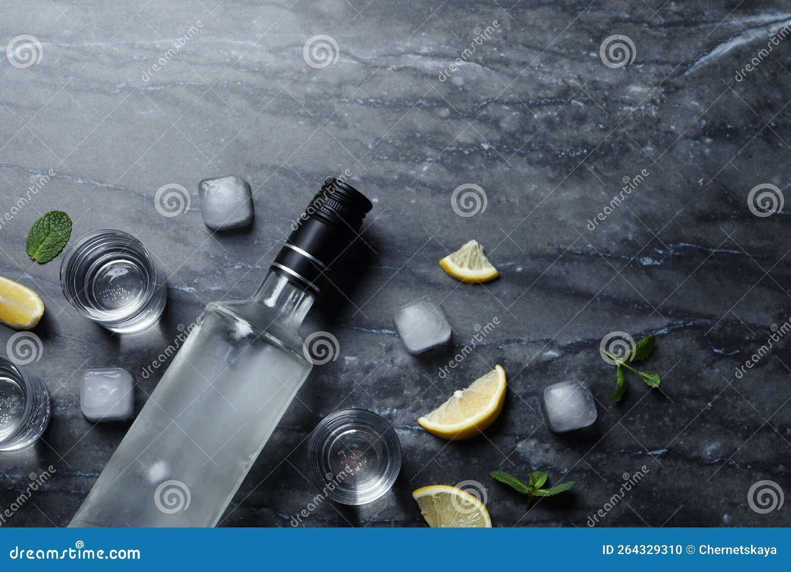 Bottle of Vodka, Shot Glasses, Lemon, Mint and Ice on Black Marble ...