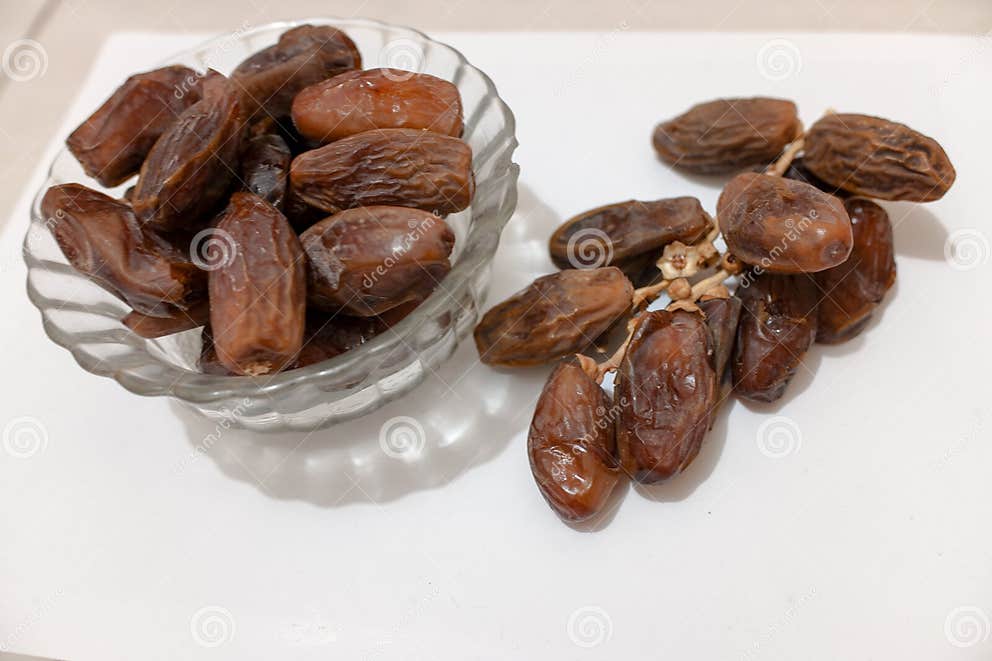 A Bowl Containing Dates and Several Stalks of Dates on a White ...