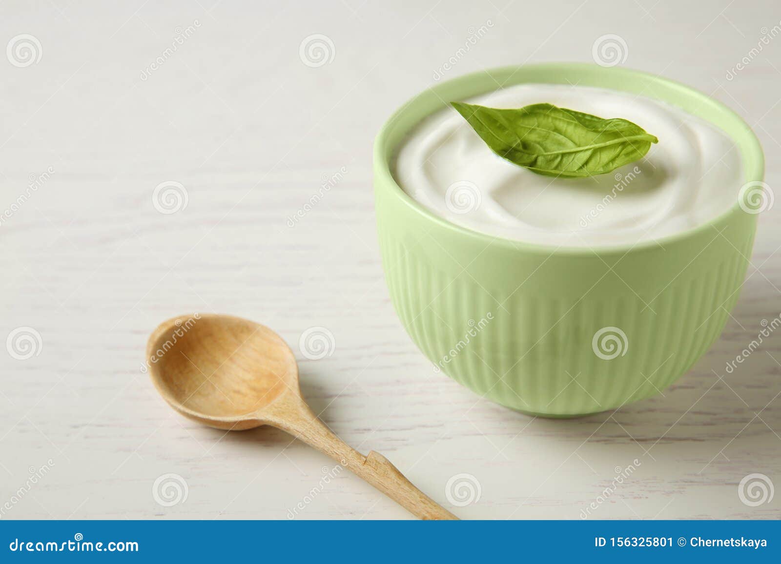 Bowl of Fresh Sour Cream with Basil and Spoon on White Wooden Table ...