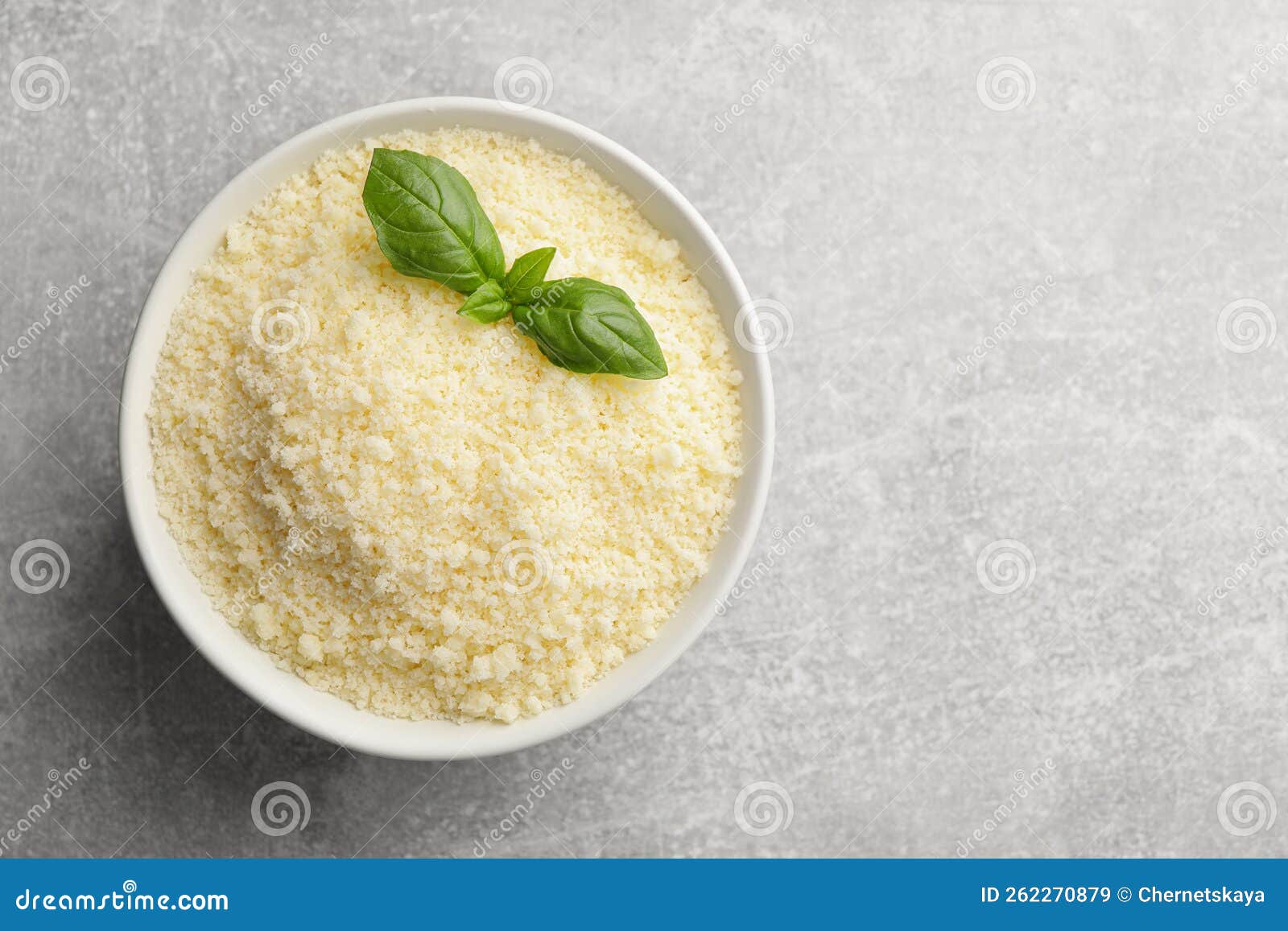 Bowl with Grated Parmesan Cheese and Basil on Grey Table, Top View ...