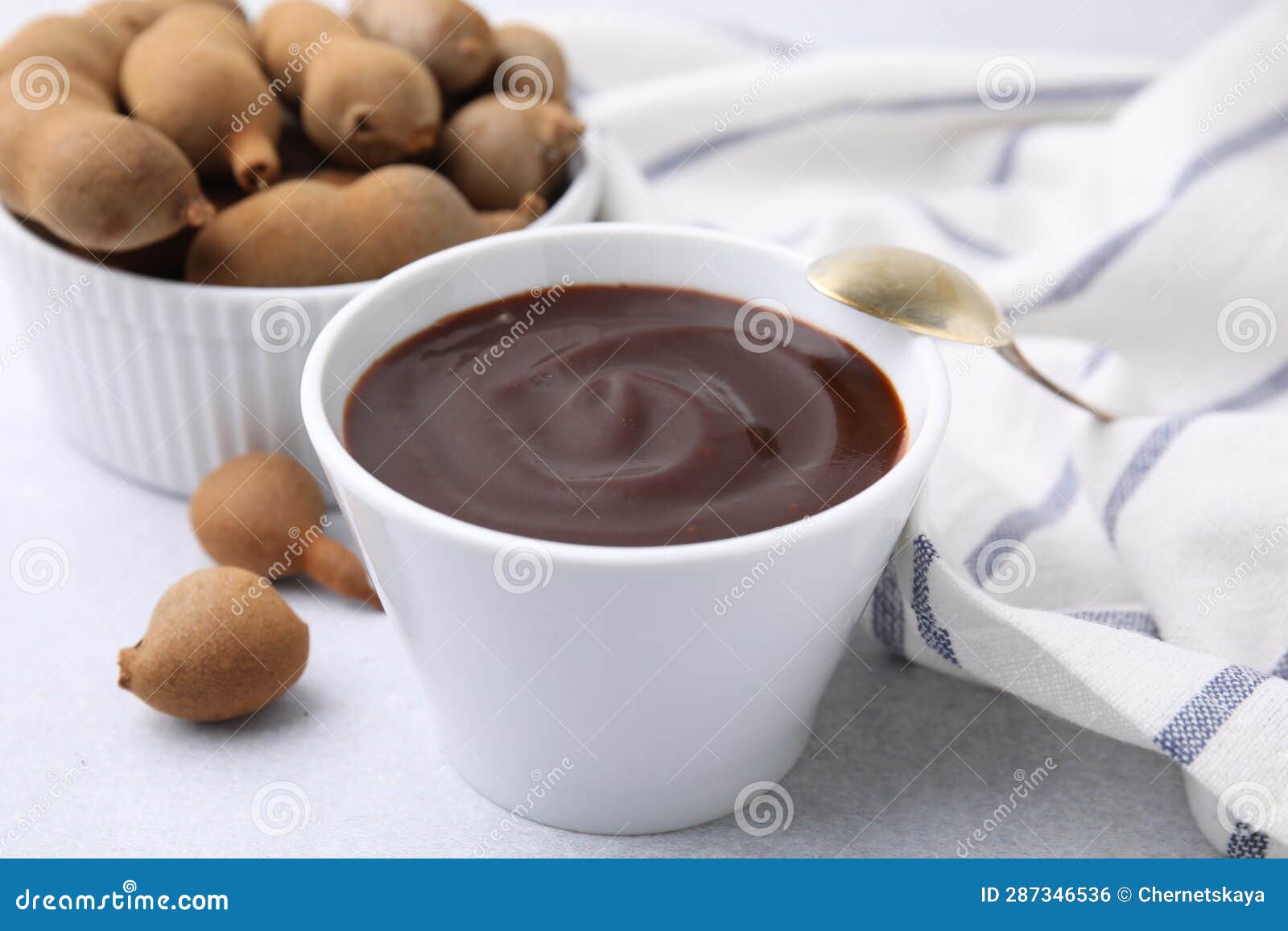 Bowl of Tamarind Sauce, Spoon and Fresh Pods on Light Table, Closeup ...