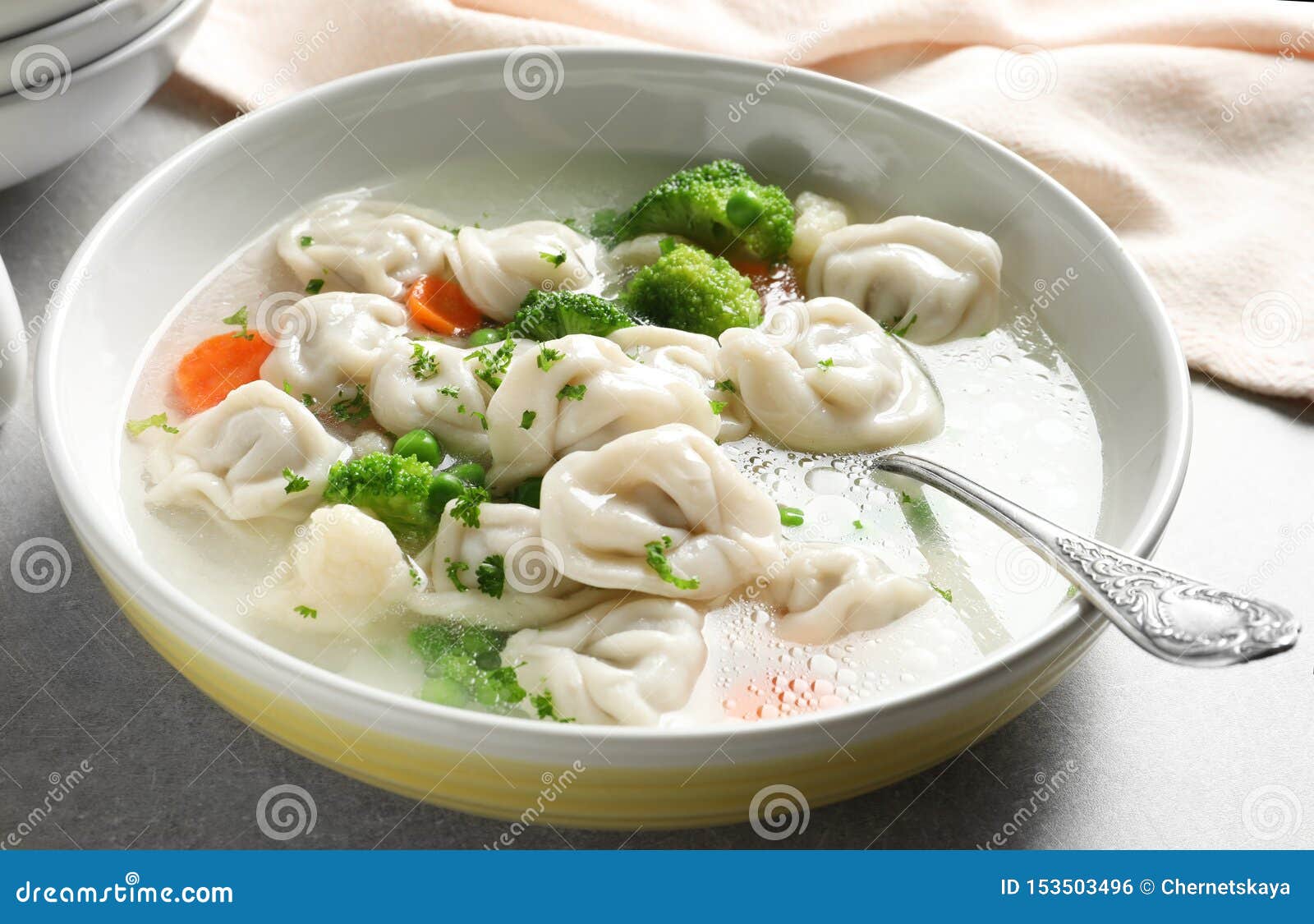 Bowl Of Tasty Dumplings In Broth With Spoon On Table Stock Photo ...