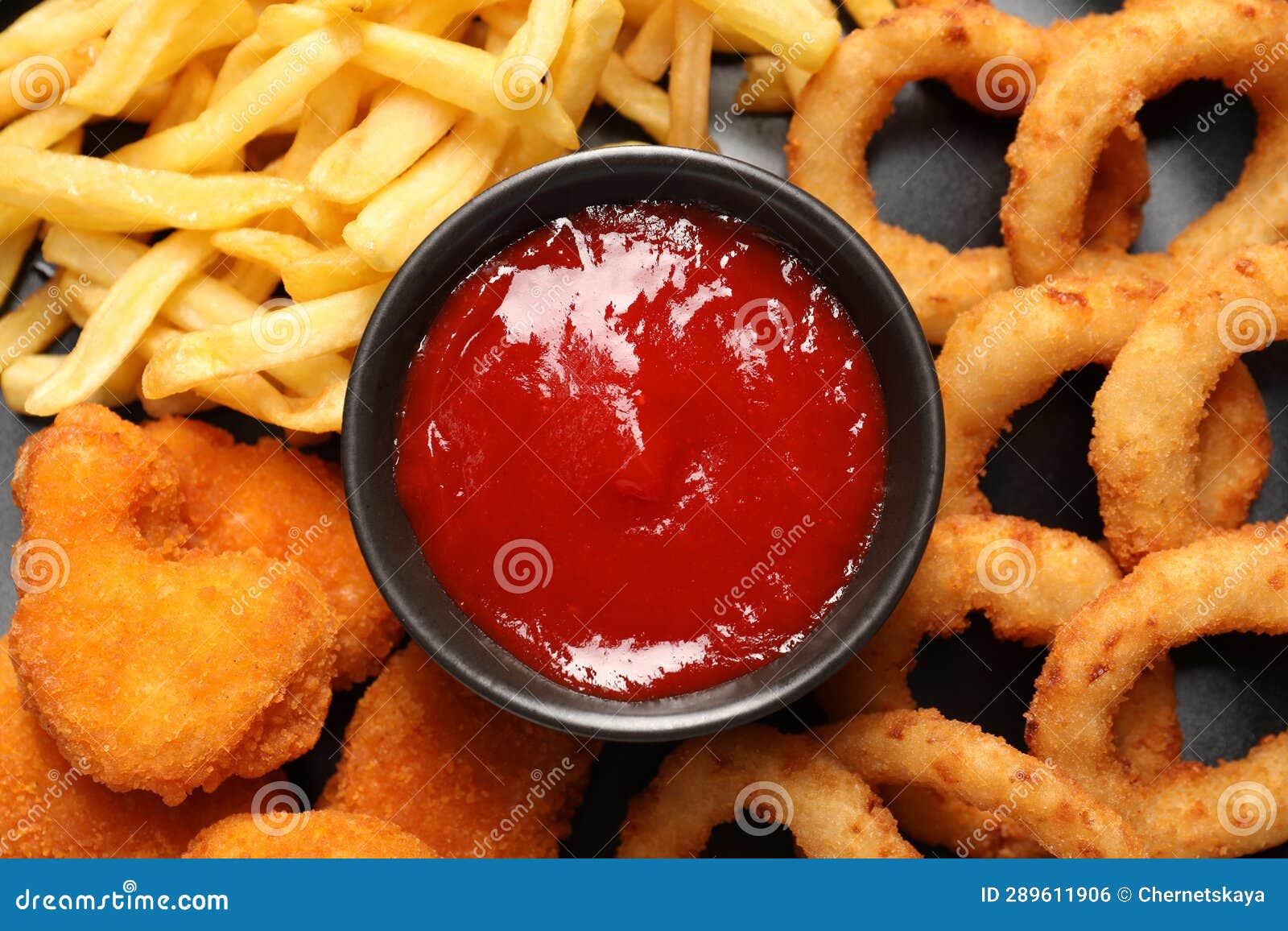 Bowl with Tomato Ketchup and Different Snacks on Dark Table, Closeup ...