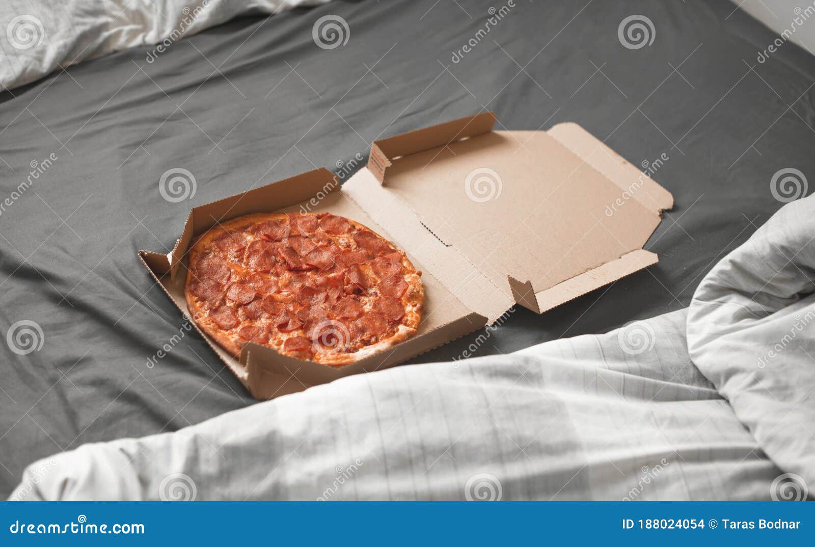 Box with an Appetizing Pizza on the Bed. Delivery of Pizza Concept ...