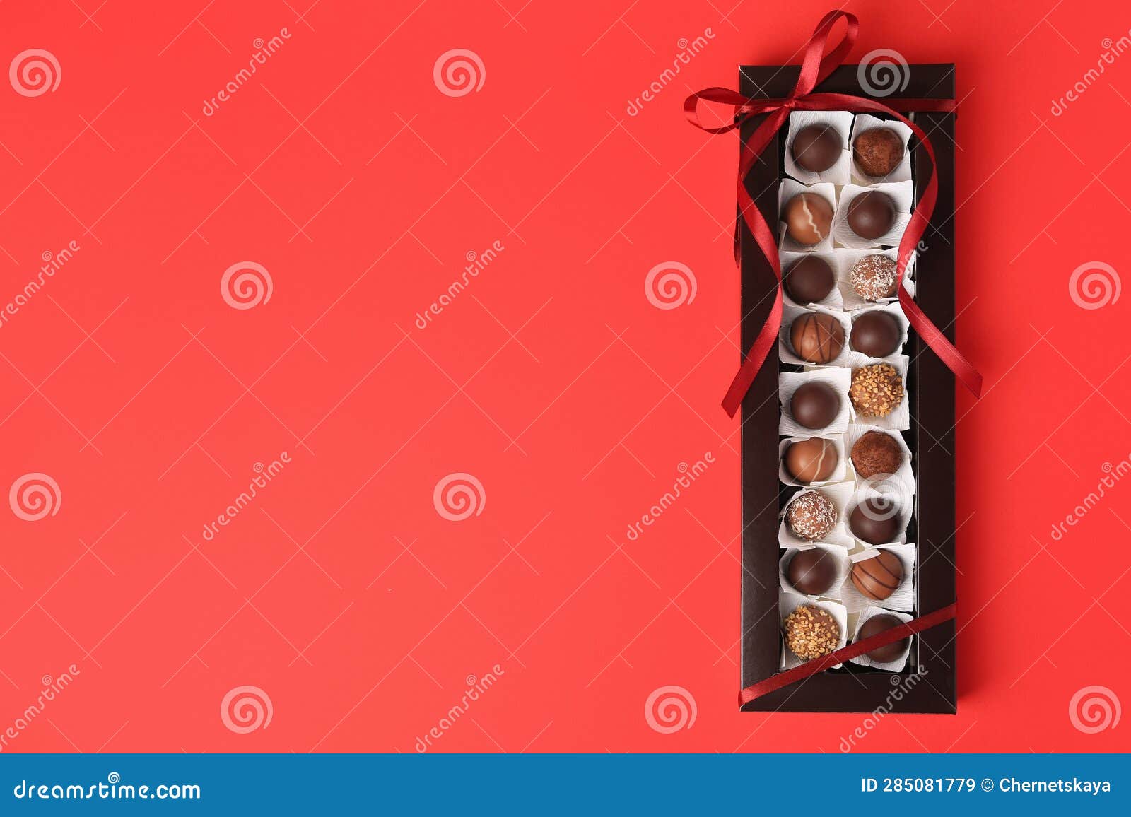 Box with Delicious Chocolate Candies on Red Table, Top View. Space for ...