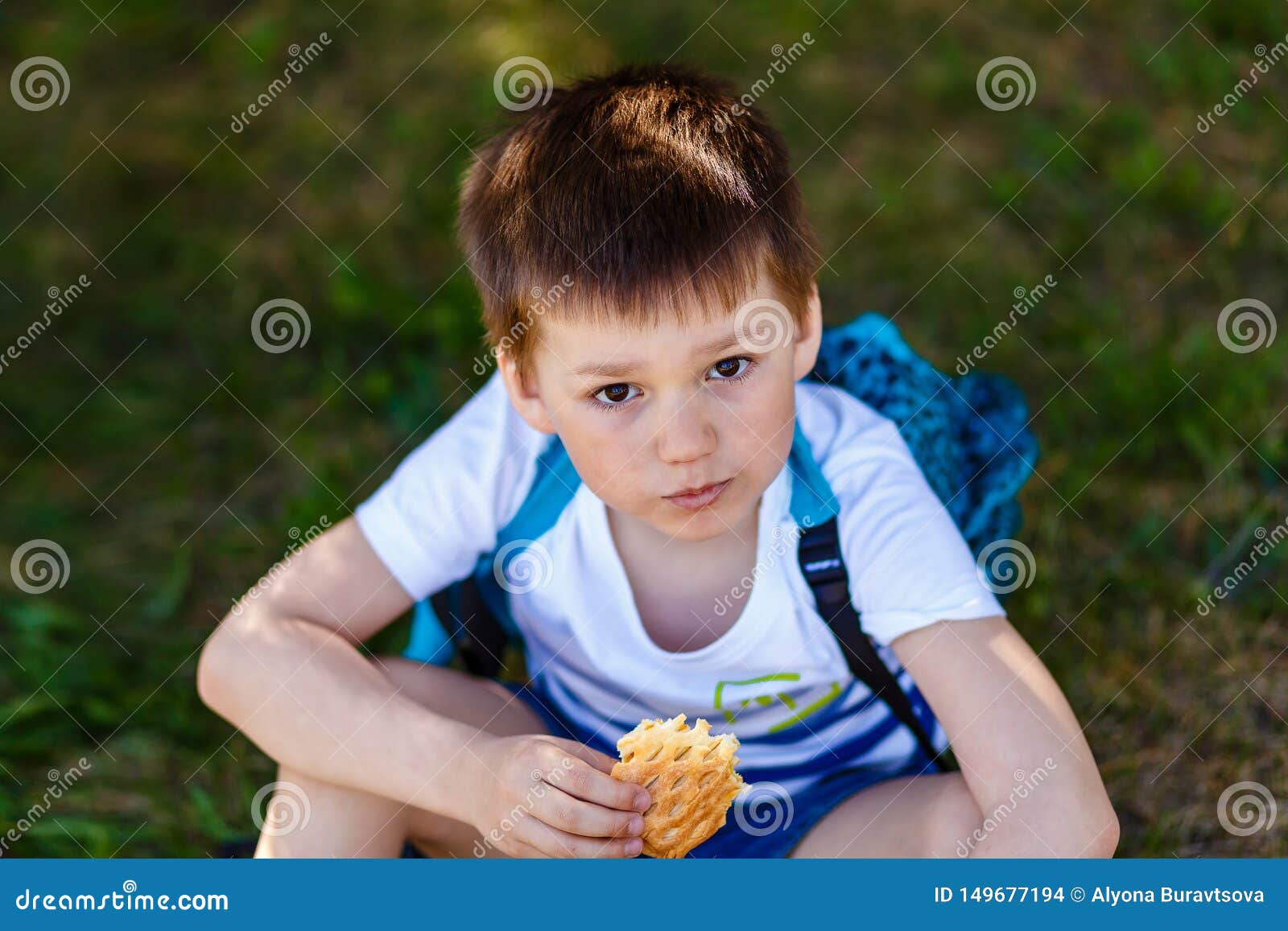 Boy with backpack eats bun stock photo. Image of break - 149677194